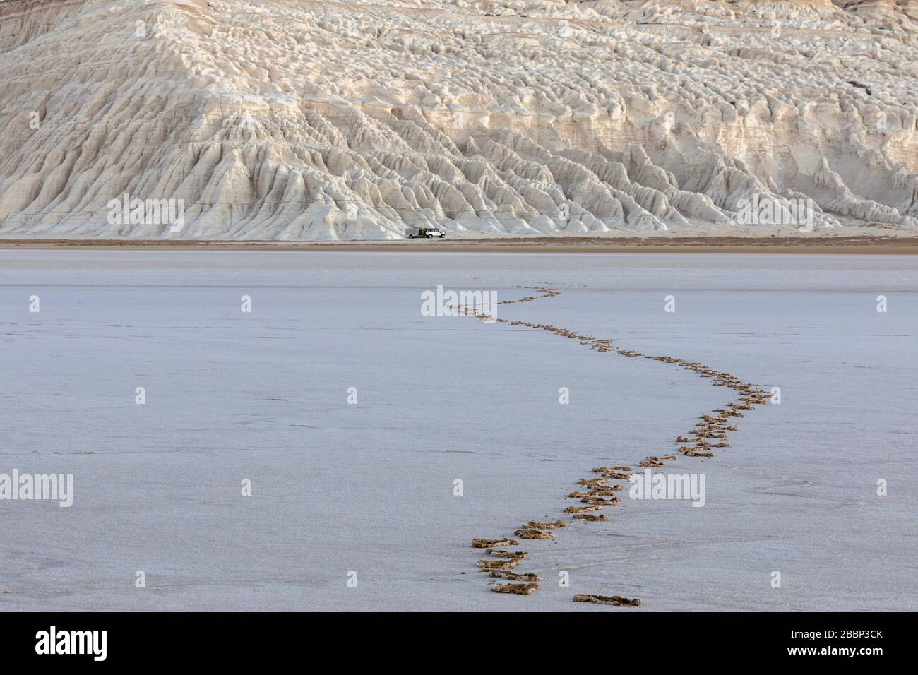 Foot traces in the soft salty ground leading to white rock formations ...