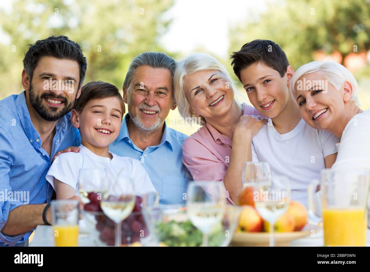 Family sitting having lunch in garden Stock Photo - Alamy