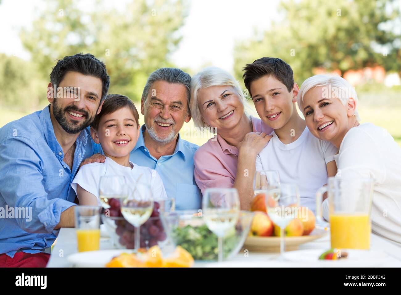Family sitting having lunch in garden Stock Photo - Alamy