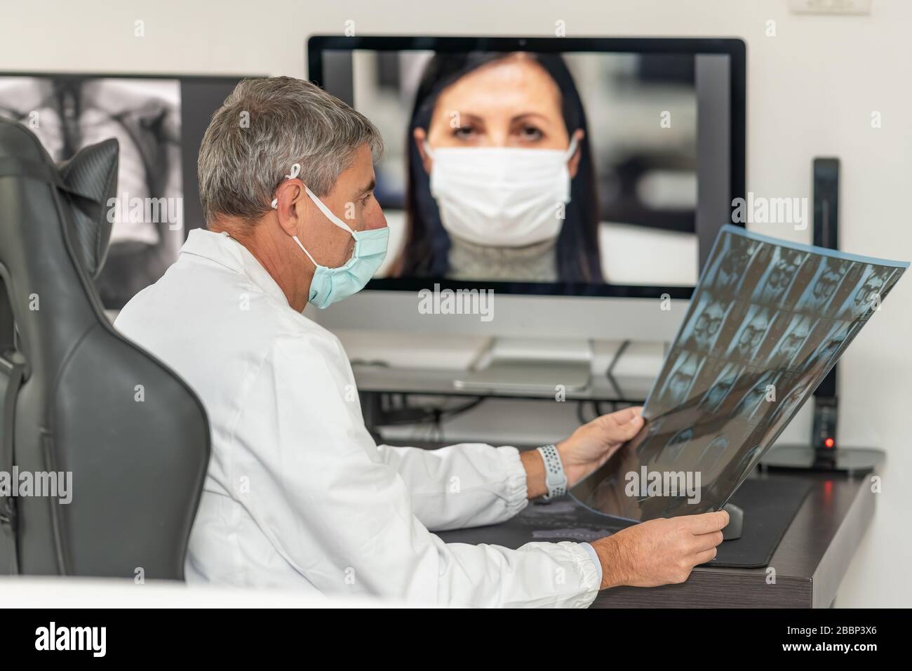 Back view of doctor making video call with his patient at home wearing ...