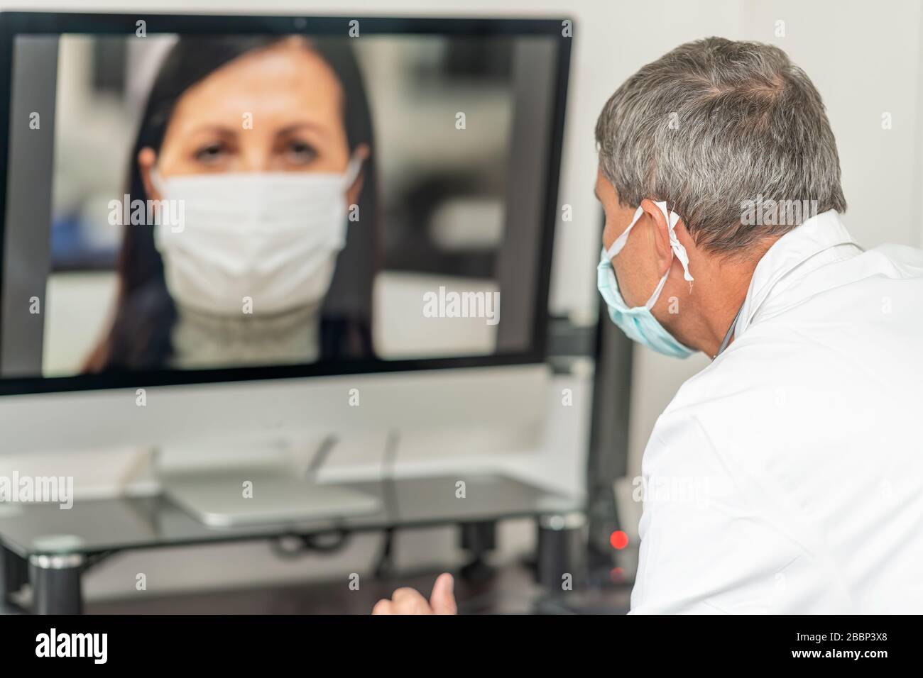 Back view of doctor making video call with his patient at home with ...