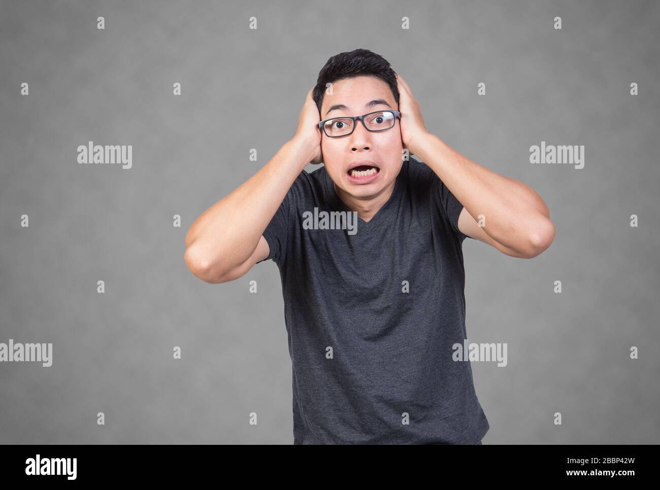 man scream shocked face hand on head grey background Stock Photo - Alamy