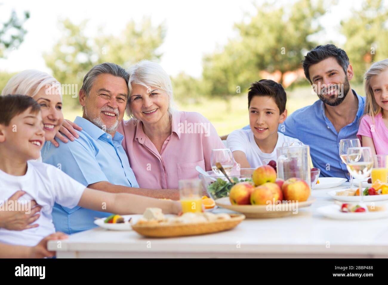 Family sitting having lunch in garden Stock Photo - Alamy