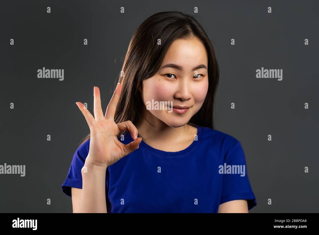 Young asian woman making OK sign over grey background. Winner. Success ...