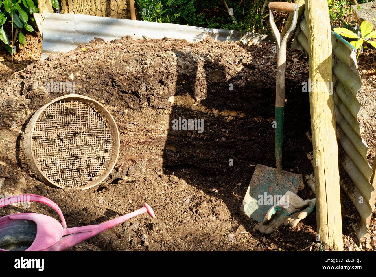 A compost heap with a soil sieve, watering can and shovel Stock Photo ...