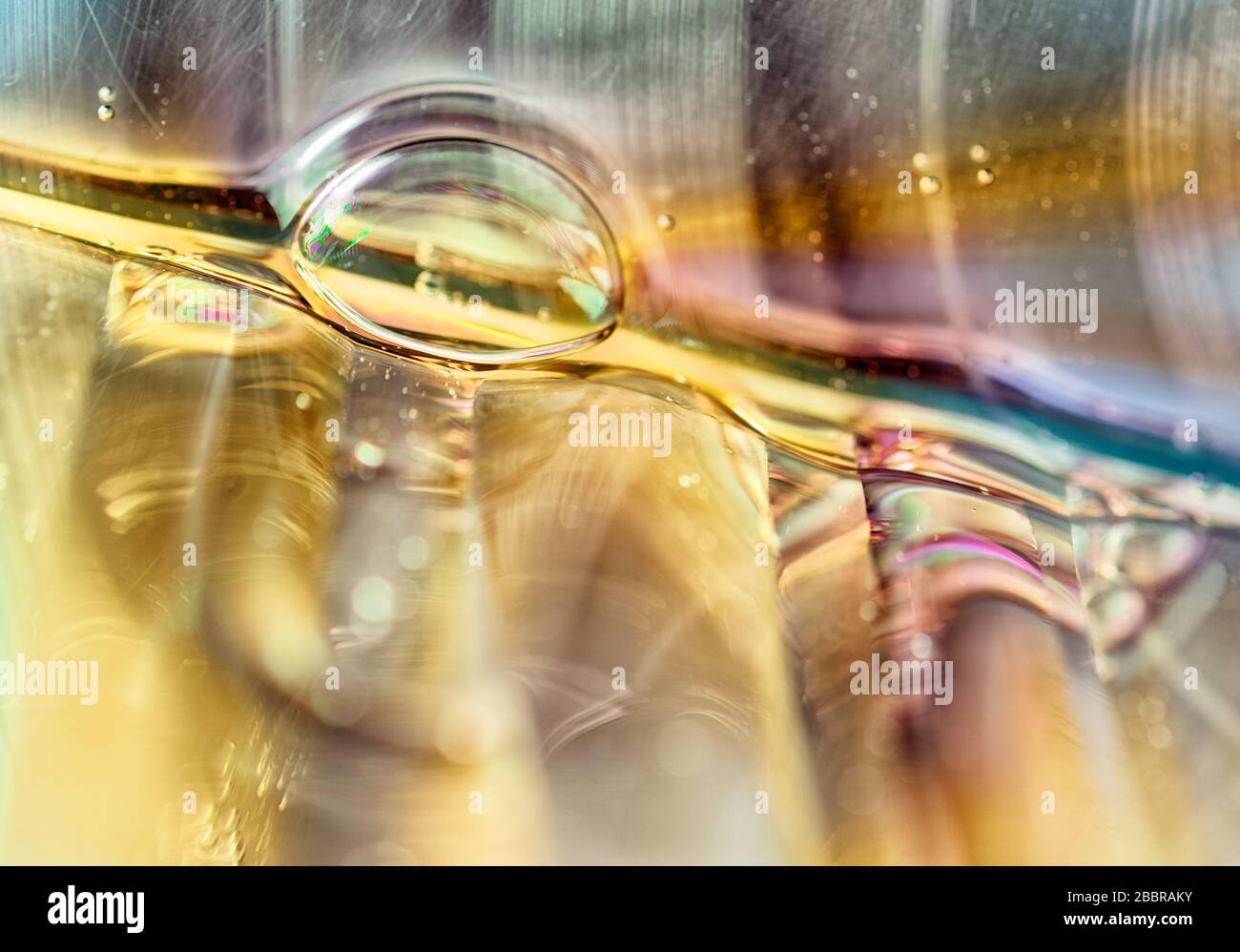 Colorful translucent golden liquid with air bubbles dripping on ...