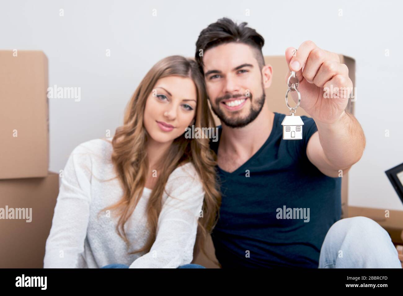 Young smiling couple holding their new house keys, real estate and ...
