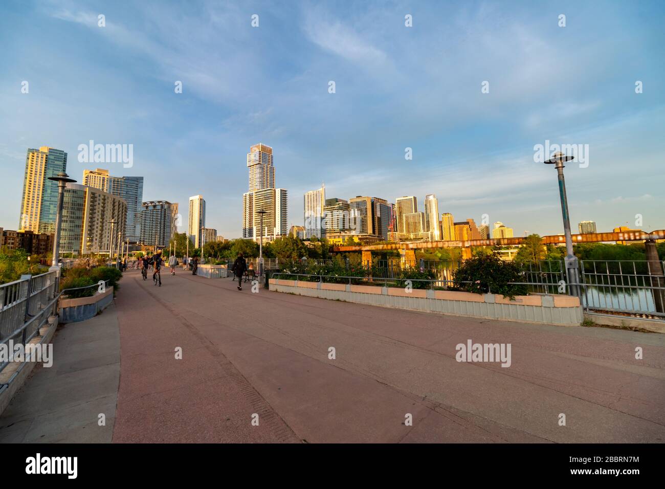 Multiple People and Bicycles Crossing Pedestrian Bridge With Downtown ...