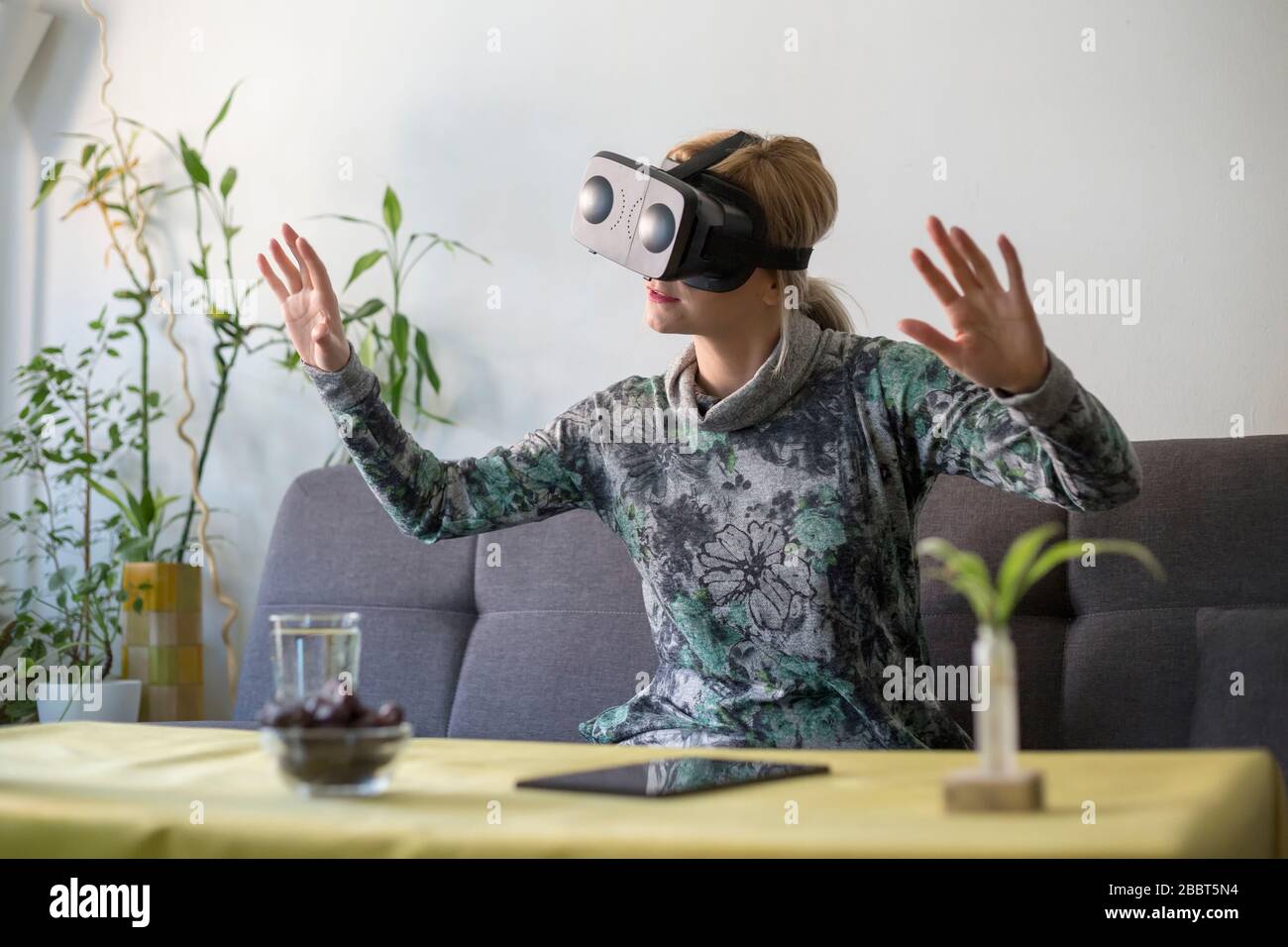 woman at home enjoying virtual reality goggles on sofa Looking around ...