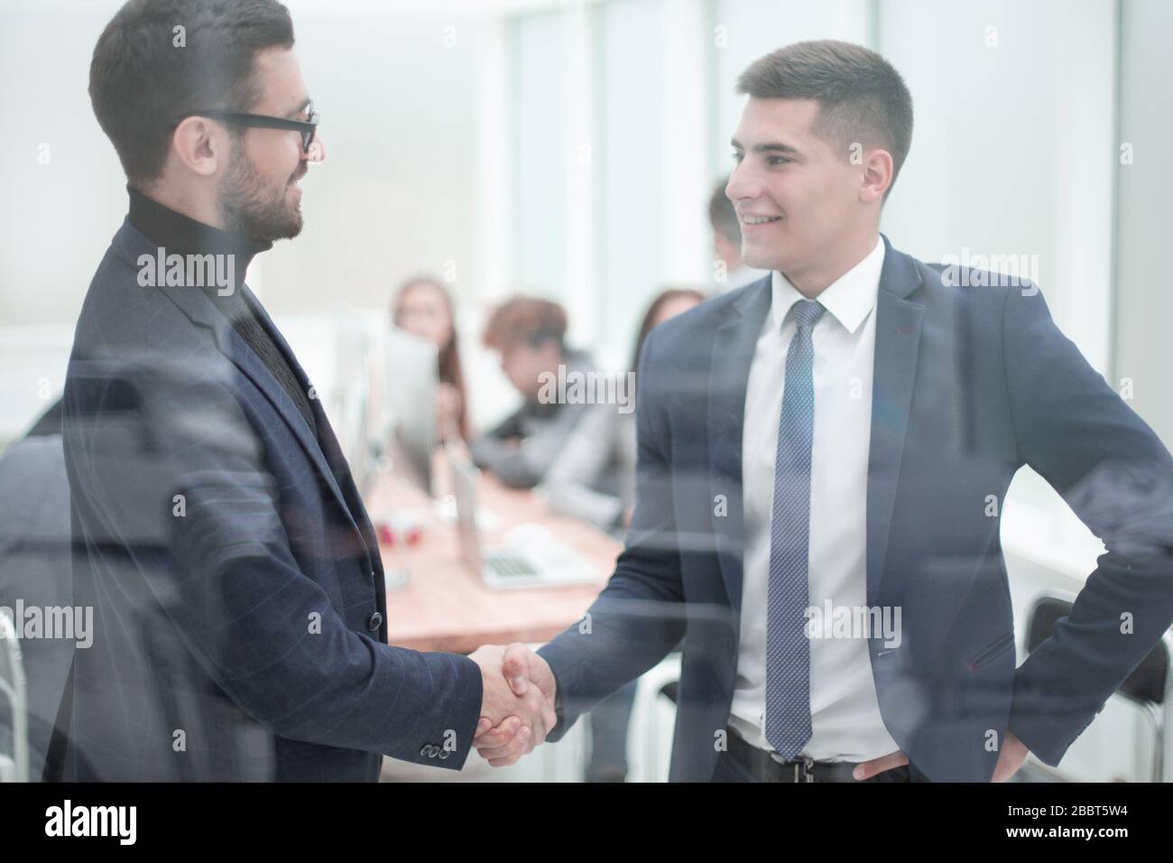 through the glass. business partners handshake in the office Stock ...
