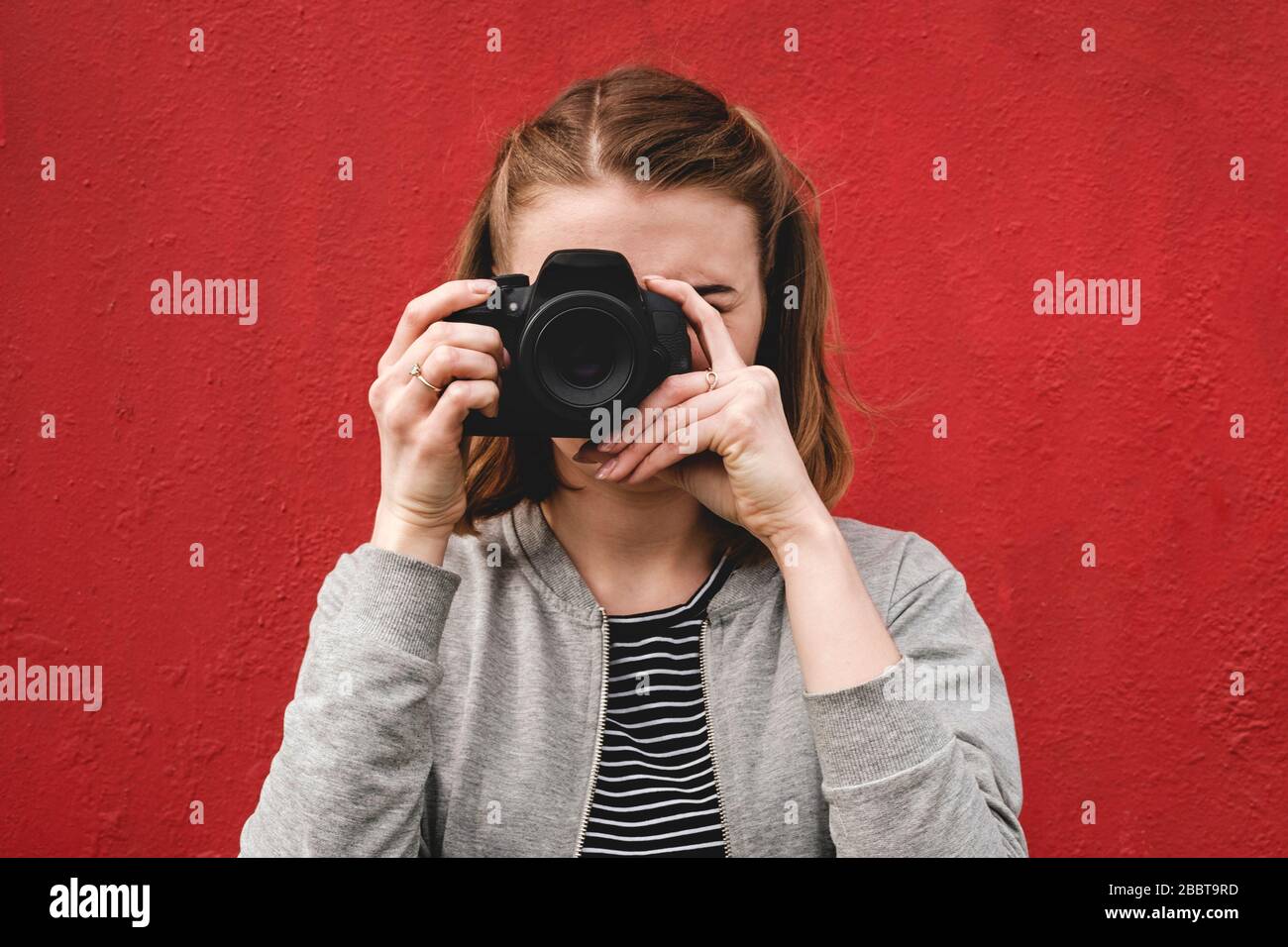 Young woman photographer focusing on the viewer Stock Photo - Alamy