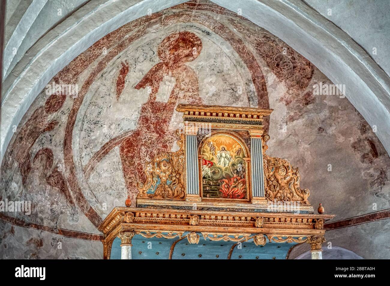 The apse of an old romanesque church with golden reredos and a mural ...