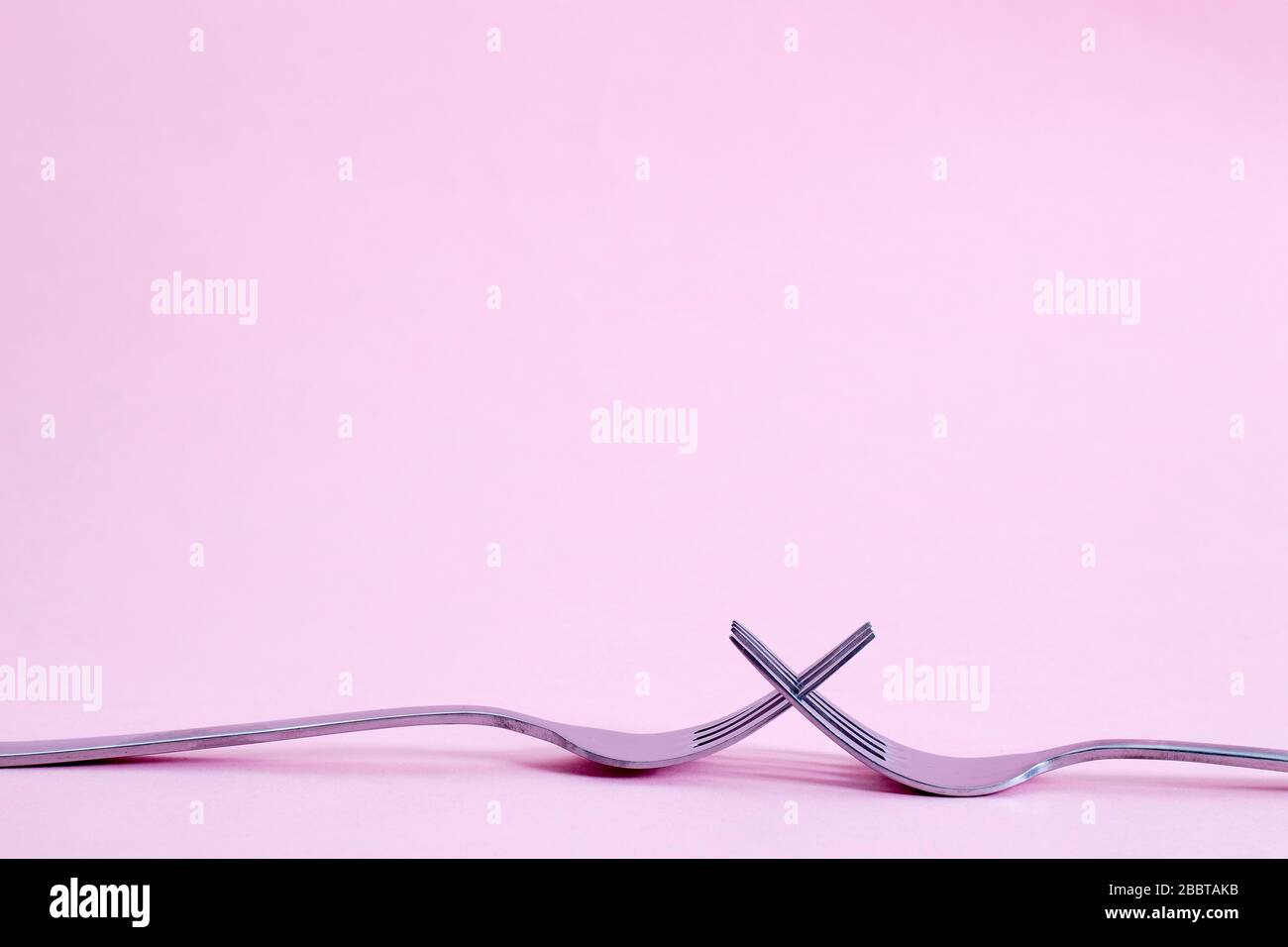 Two crossed forks on a pink background as a connection concept Stock ...