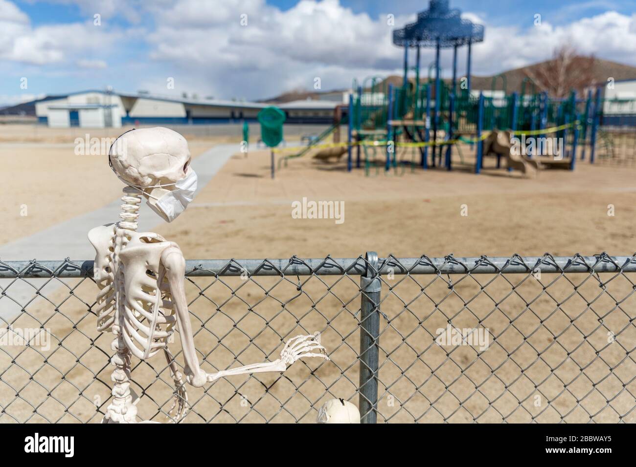 Skeleton behind fence looking at an empty closed park on a nice day ...