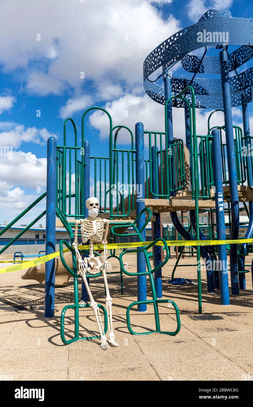 Adult skeleton sitting on playground equipment at an empty closed park ...