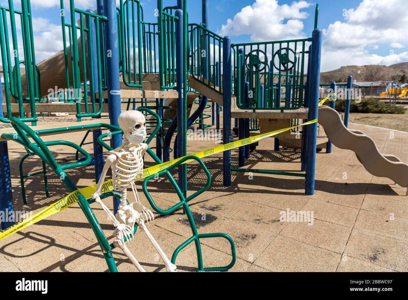Adult skeleton sitting on playground equipment at an empty closed park ...