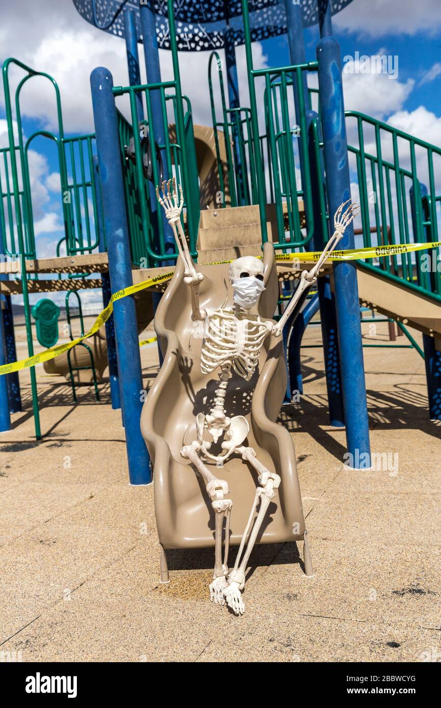 Adult skeleton sliding on childrens toys at an empty closed park on a ...