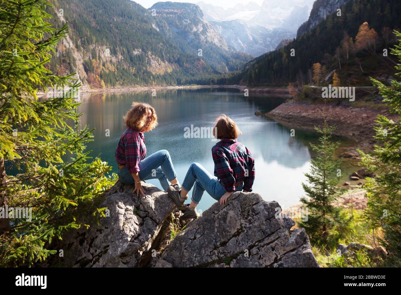 mountain trip. two happy girls on the background of a mountain lake and ...