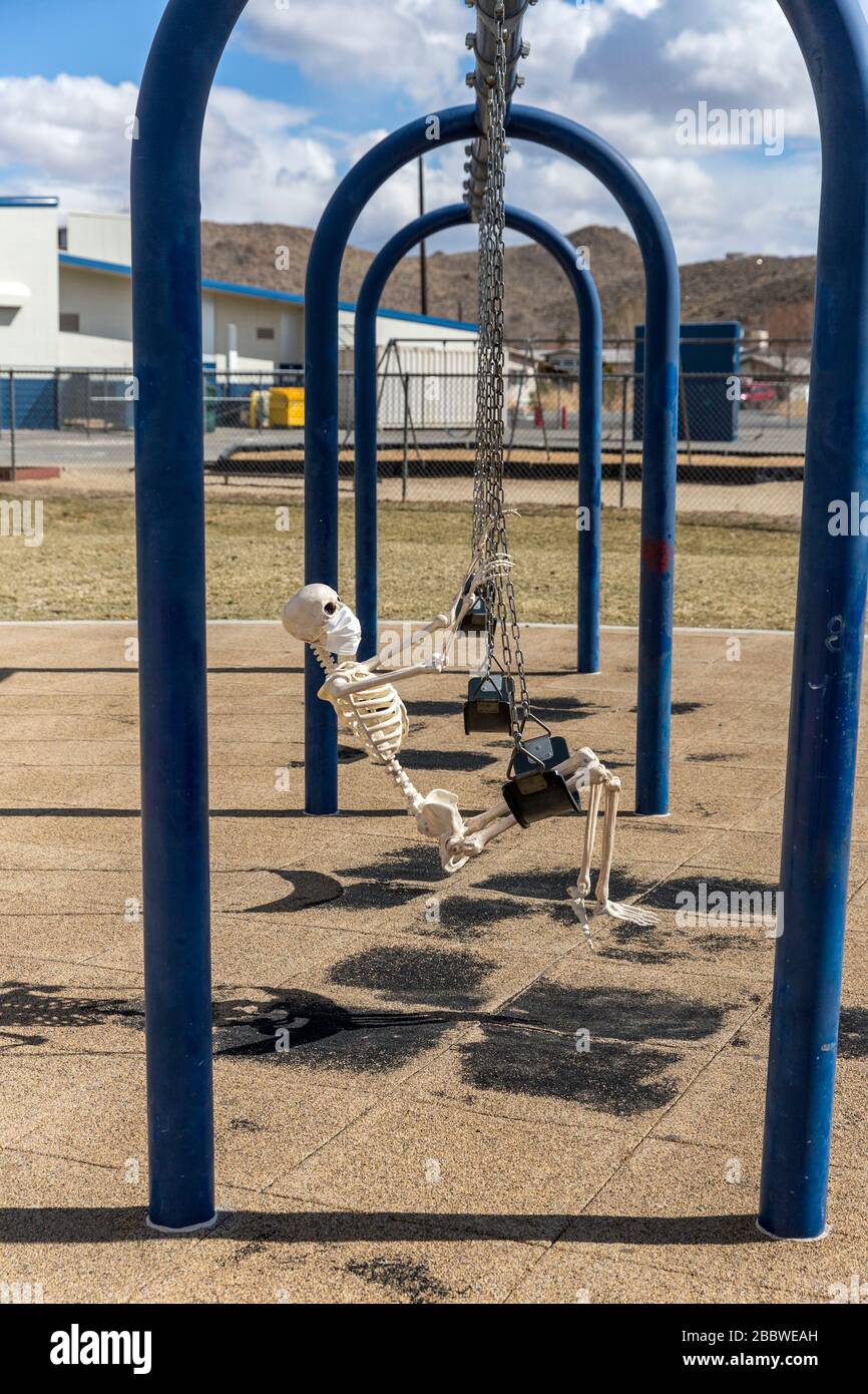 Skeleton swinging on childs toy at an empty closed park on a nice day ...