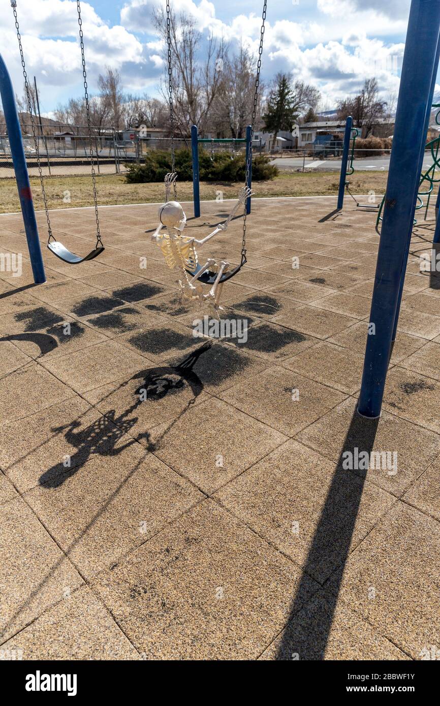 Skeleton swinging on childs toy at an empty closed park on a nice day ...