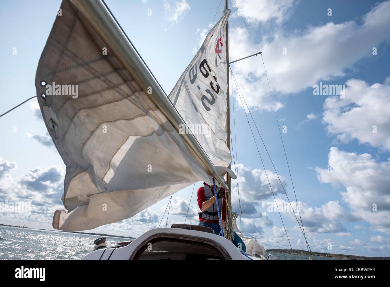 Sailor reefing the main sail doing a solo trip on a sailing boat Stock ...