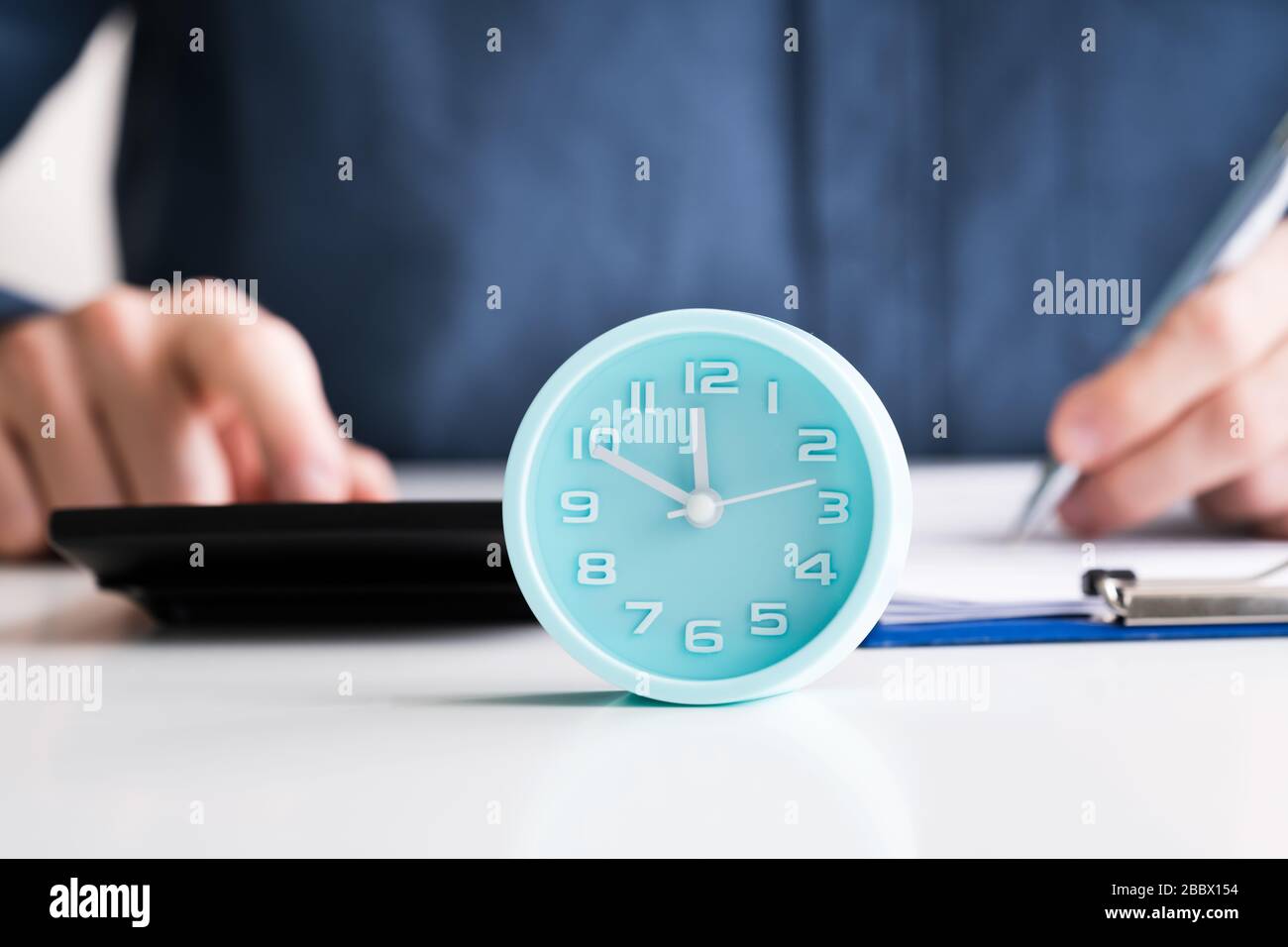 Businessperson Using Calculator For Calculating Bill With Alarm Clock ...