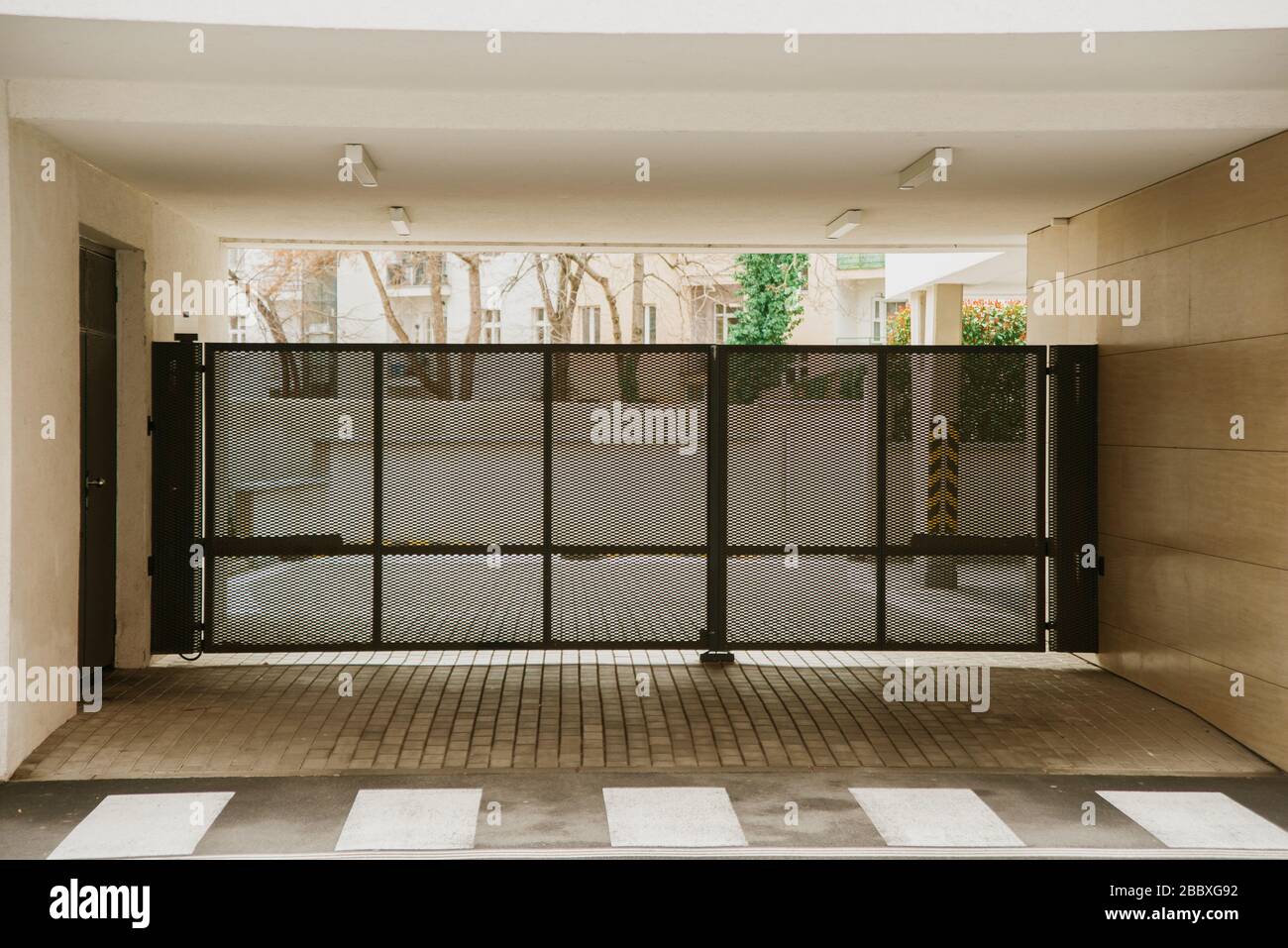 Photo of metalic black moving gate in a building gateway, safe entrance ...