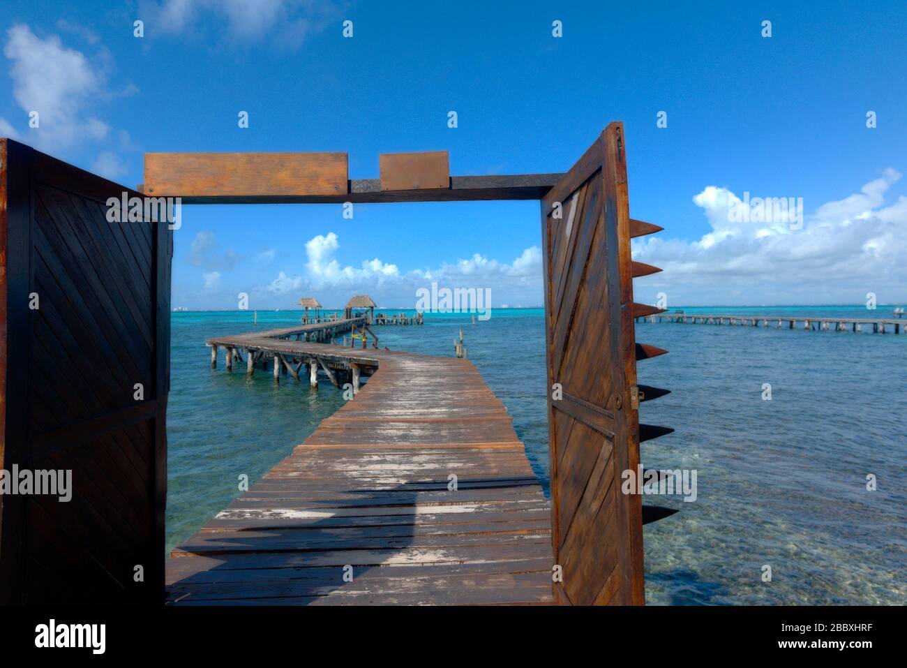 Wooden pier extending over the Caribbean sea. Open doors overlooking ...