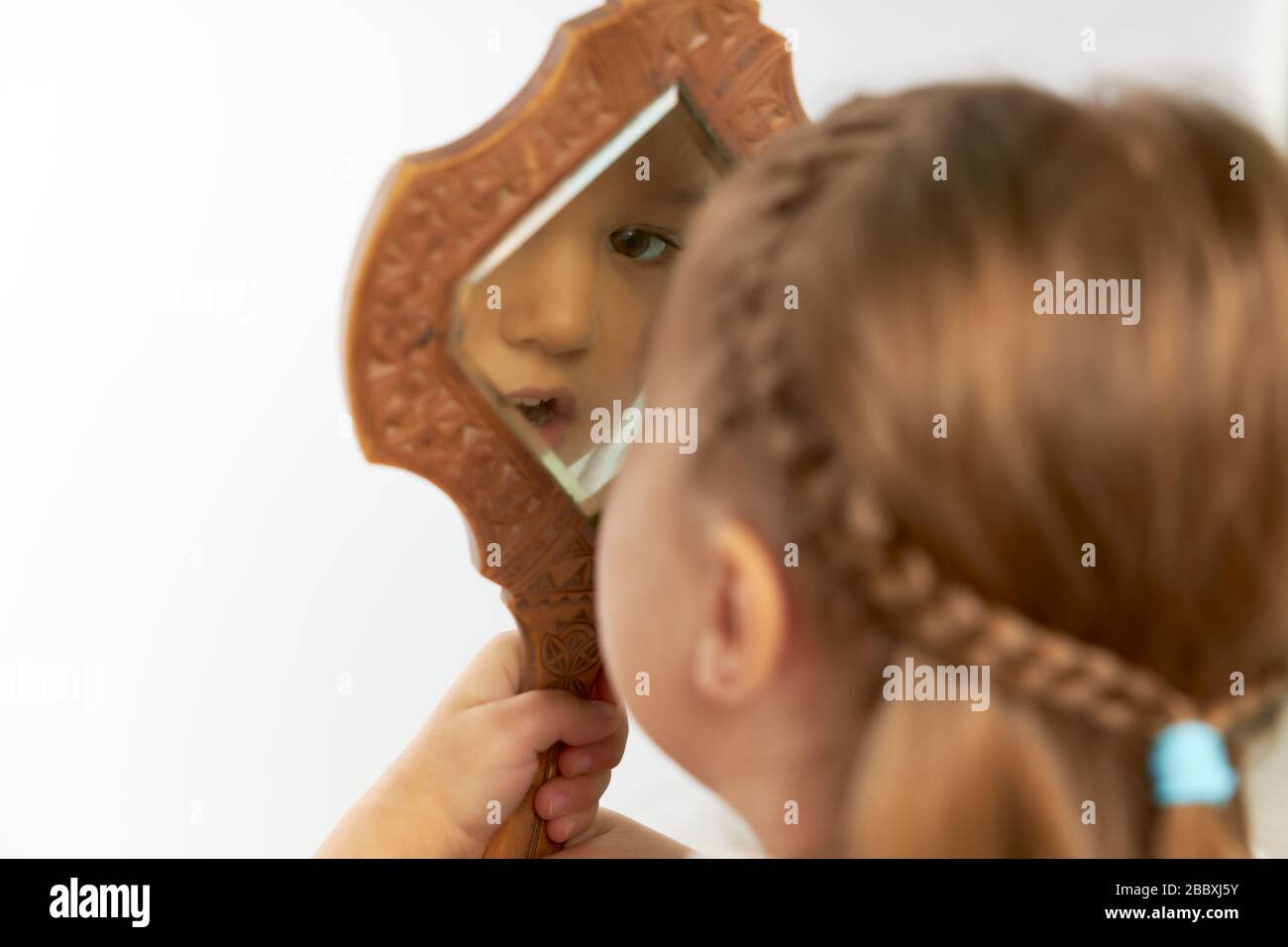 Little girl looks in the mirror in a beautiful wooden frame Stock Photo ...