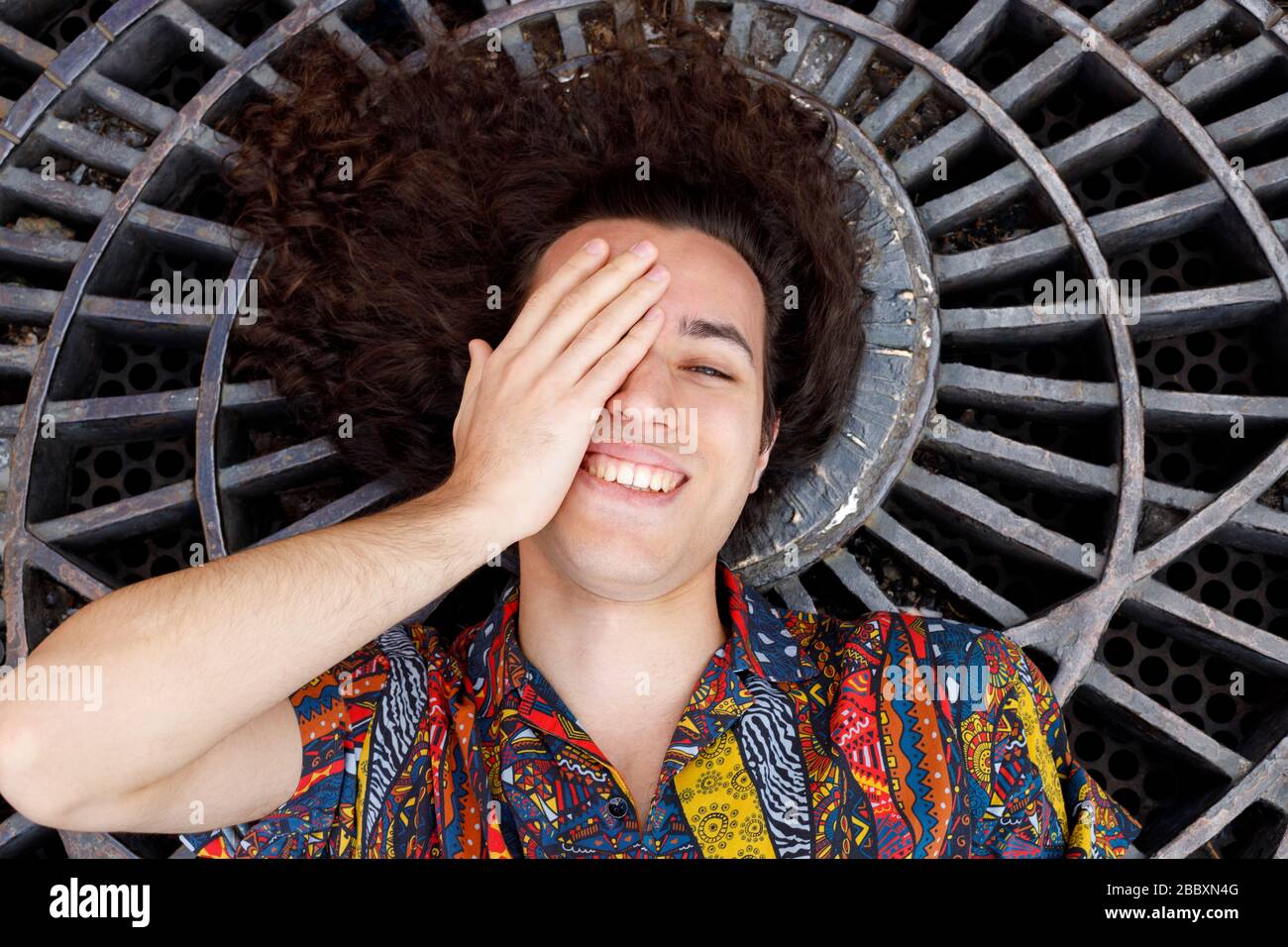 Smiling young man covering one eye with his hand. Concept of happiness ...