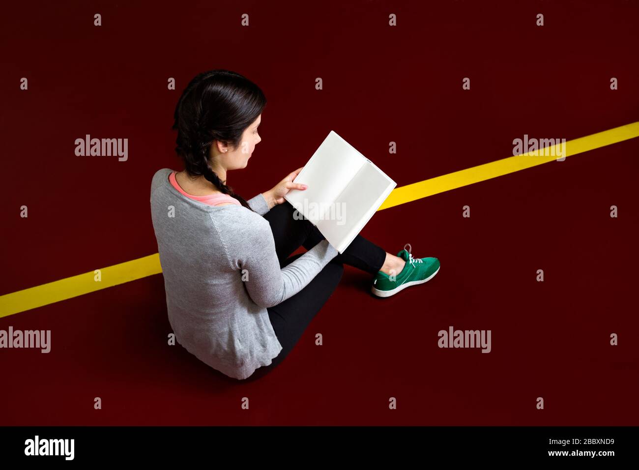 a teenager reading a book seated on the gym floor Stock Photo - Alamy