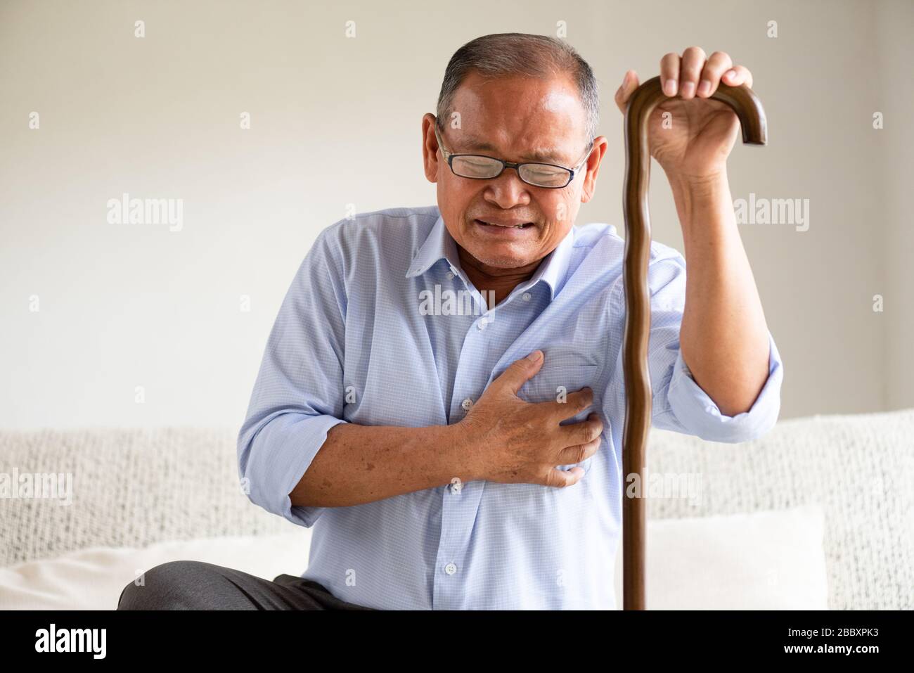 Asian old man sitting on sofa and having a with pain on heart, heart ...
