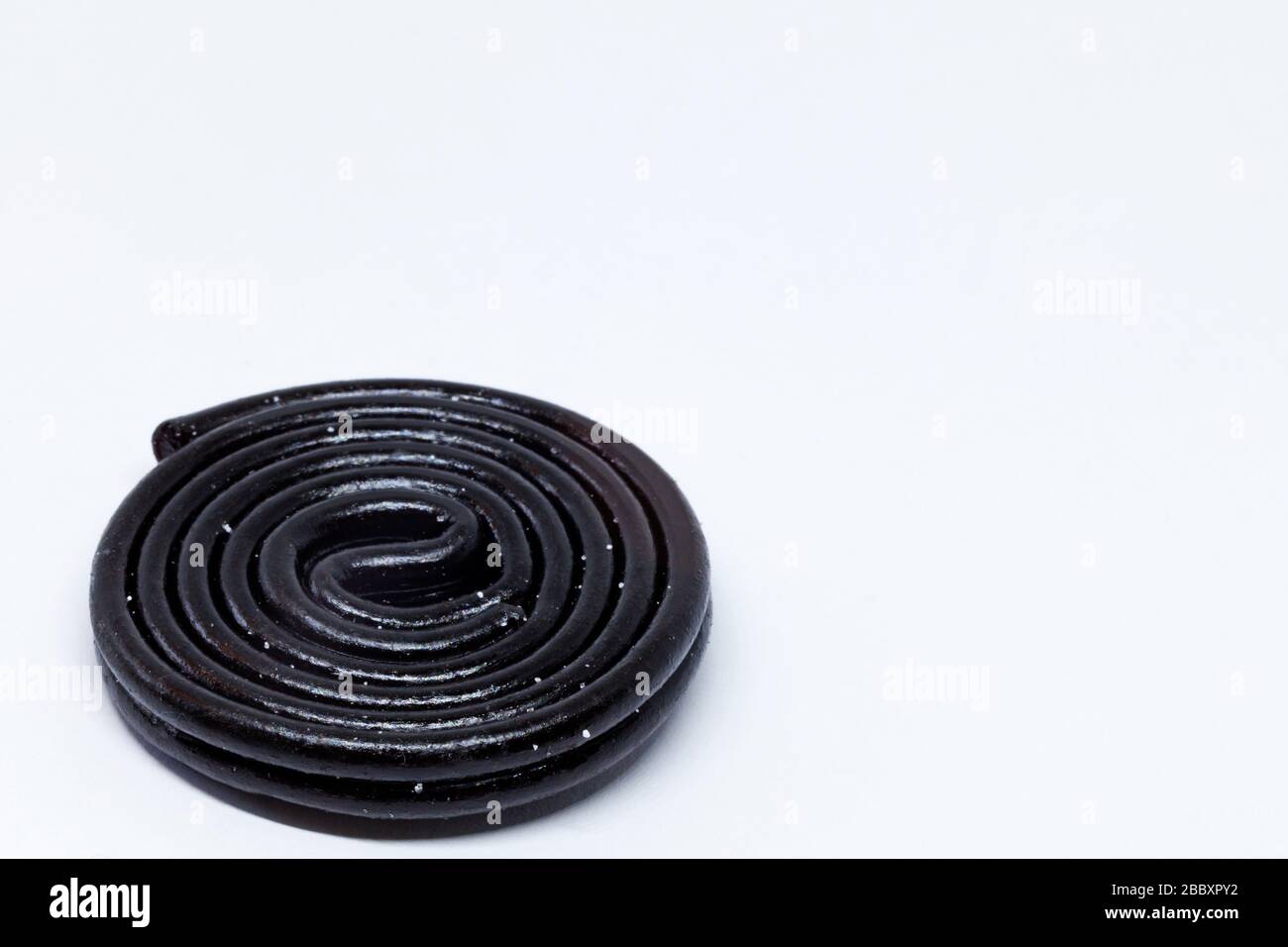 a rolled up licorice strap on white background Stock Photo - Alamy