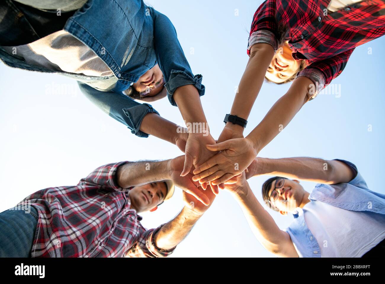 Close up bottom view of people putting their hands together. Friends ...