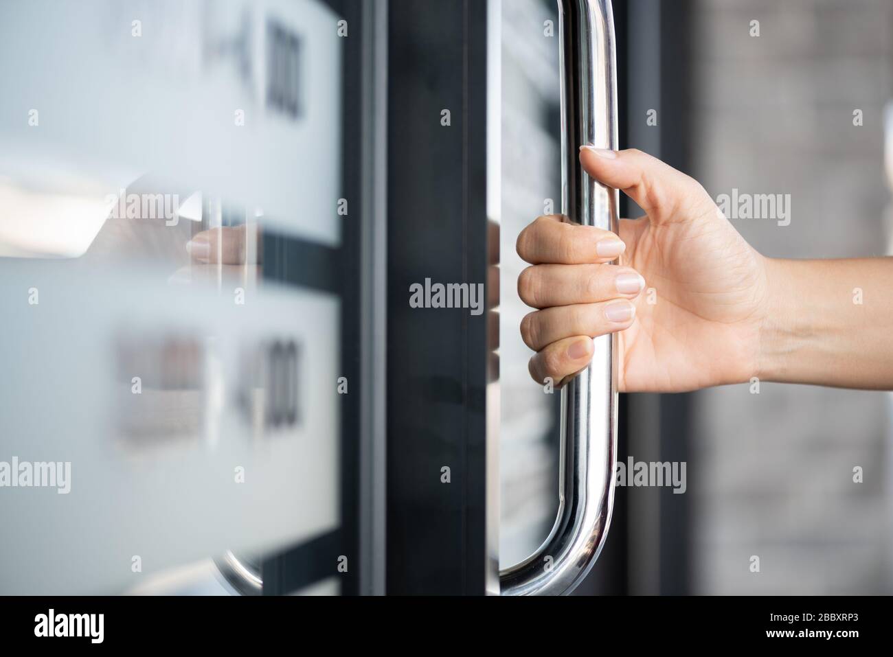 Closeup woman hand holding the door bar to open the door with glass ...