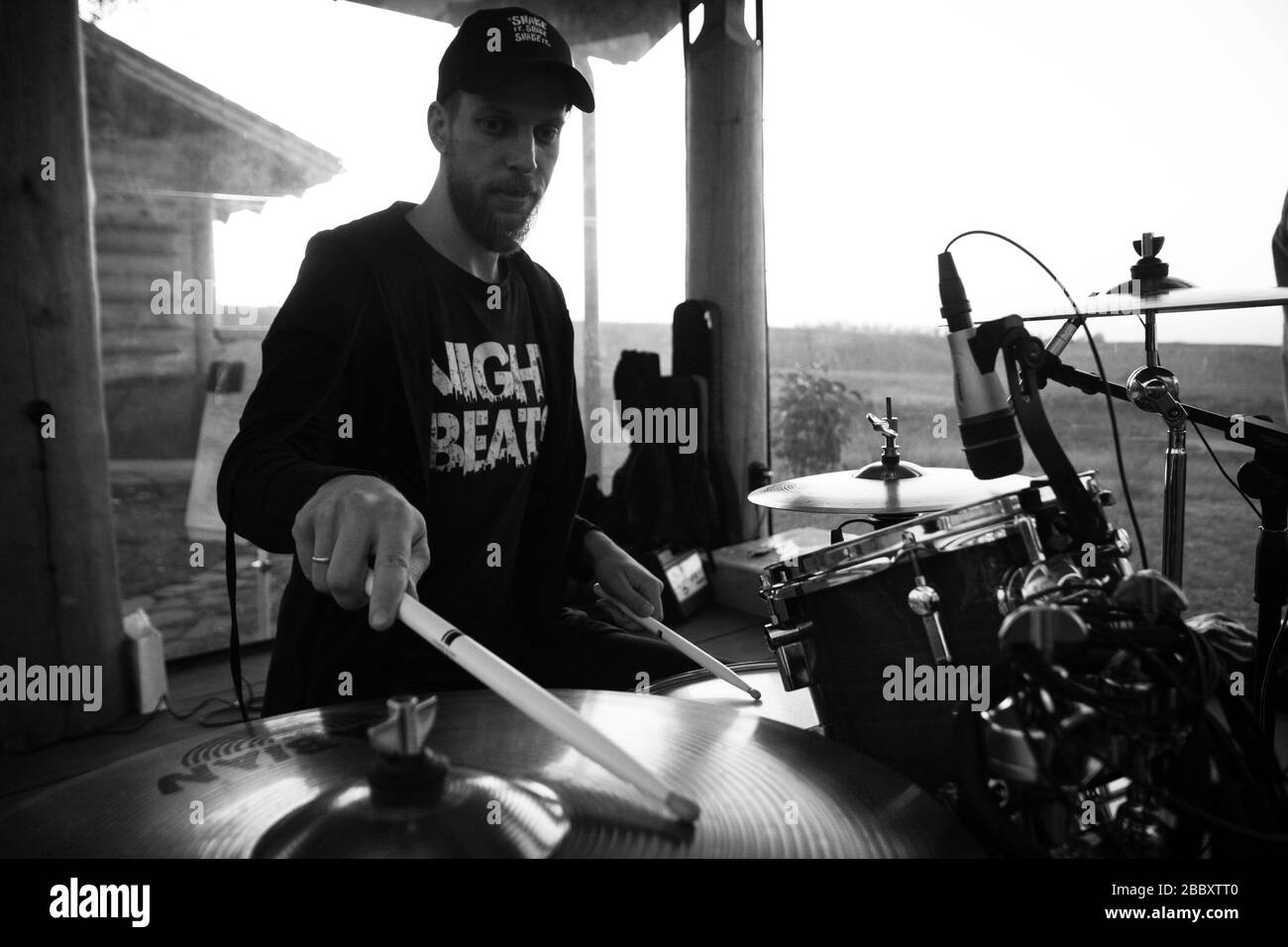 BW portrait of a beard drummer with drum sticks in his hands sitting ...