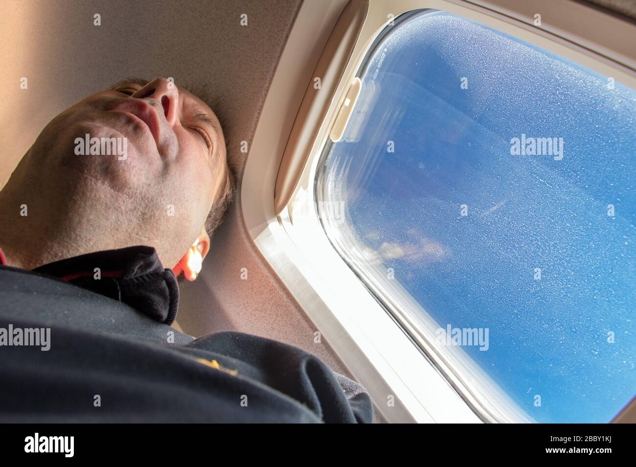 Portrait of resting passenger in flying air plane. The tired man ...