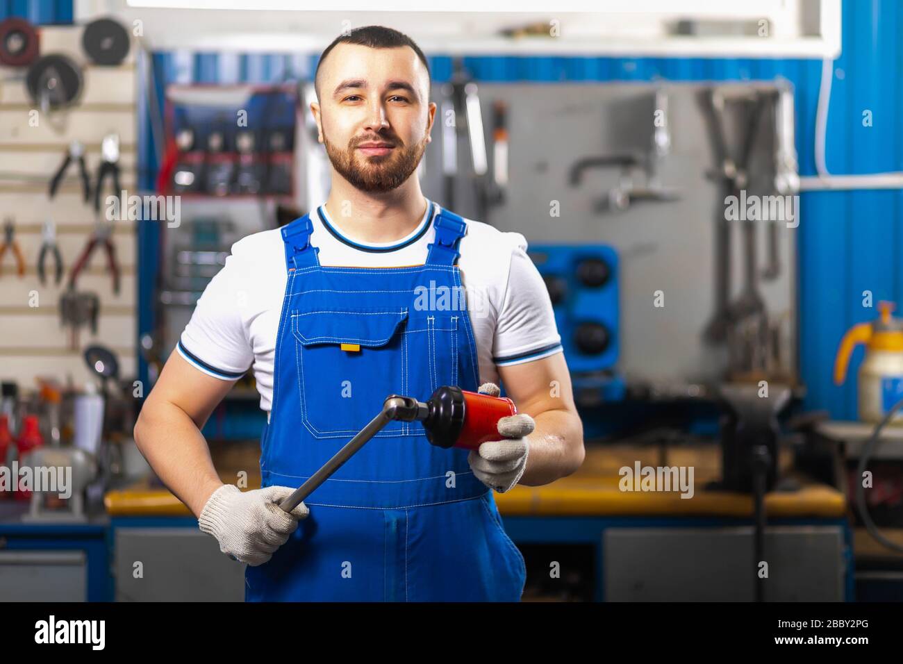 Handsome young male auto mechanic in special uniform clothes is ...
