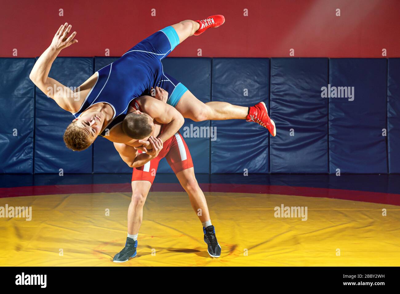 Two greco-roman wrestlers in red and blue uniform making a suplex ...