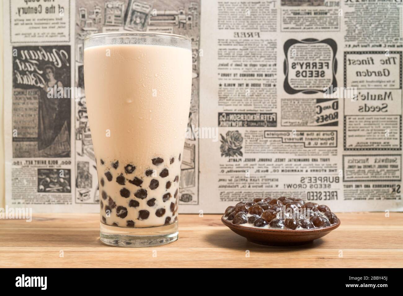A glass cup of pearl milk tea (also called bubble tea) and a plate of ...