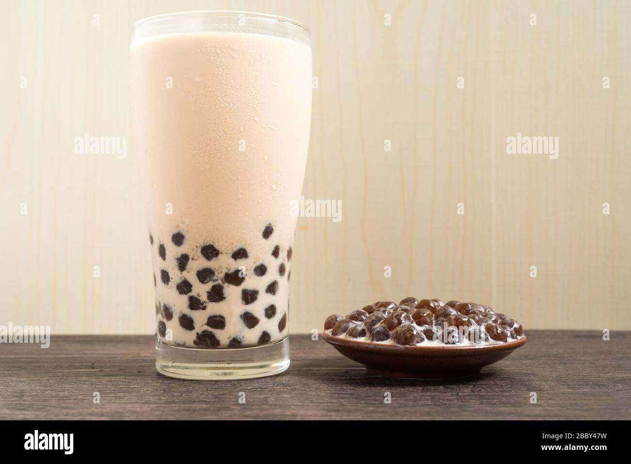 A glass cup of pearl milk tea (also called bubble tea) and a plate of ...