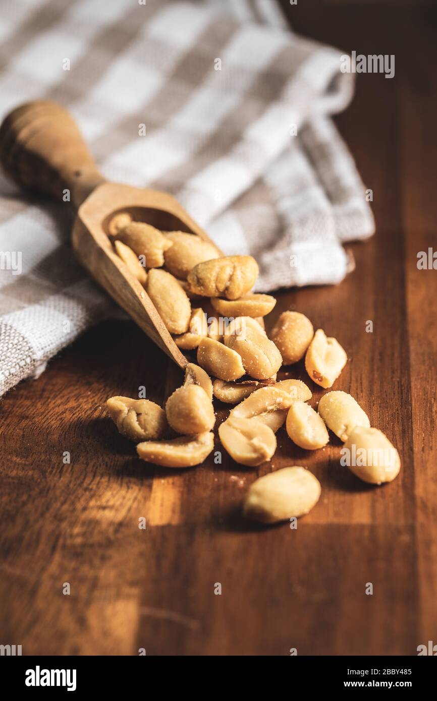 Roasted salted peanuts. Crispy nuts in scoop on wooden table Stock ...