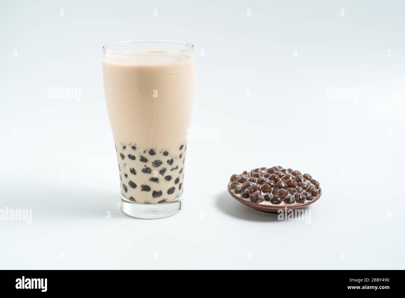 A glass cup of pearl milk tea (also called bubble tea) and a plate of ...