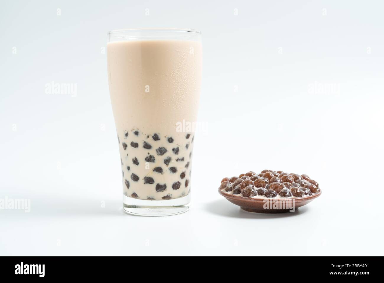 A glass cup of pearl milk tea (also called bubble tea) and a plate of ...