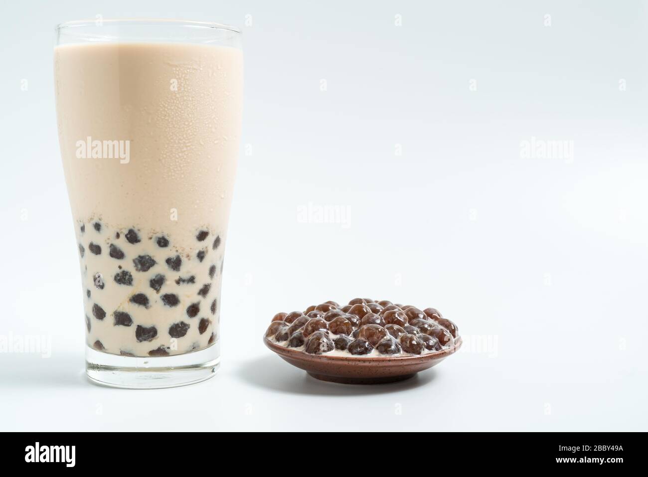 A glass cup of pearl milk tea (also called bubble tea) and a plate of ...