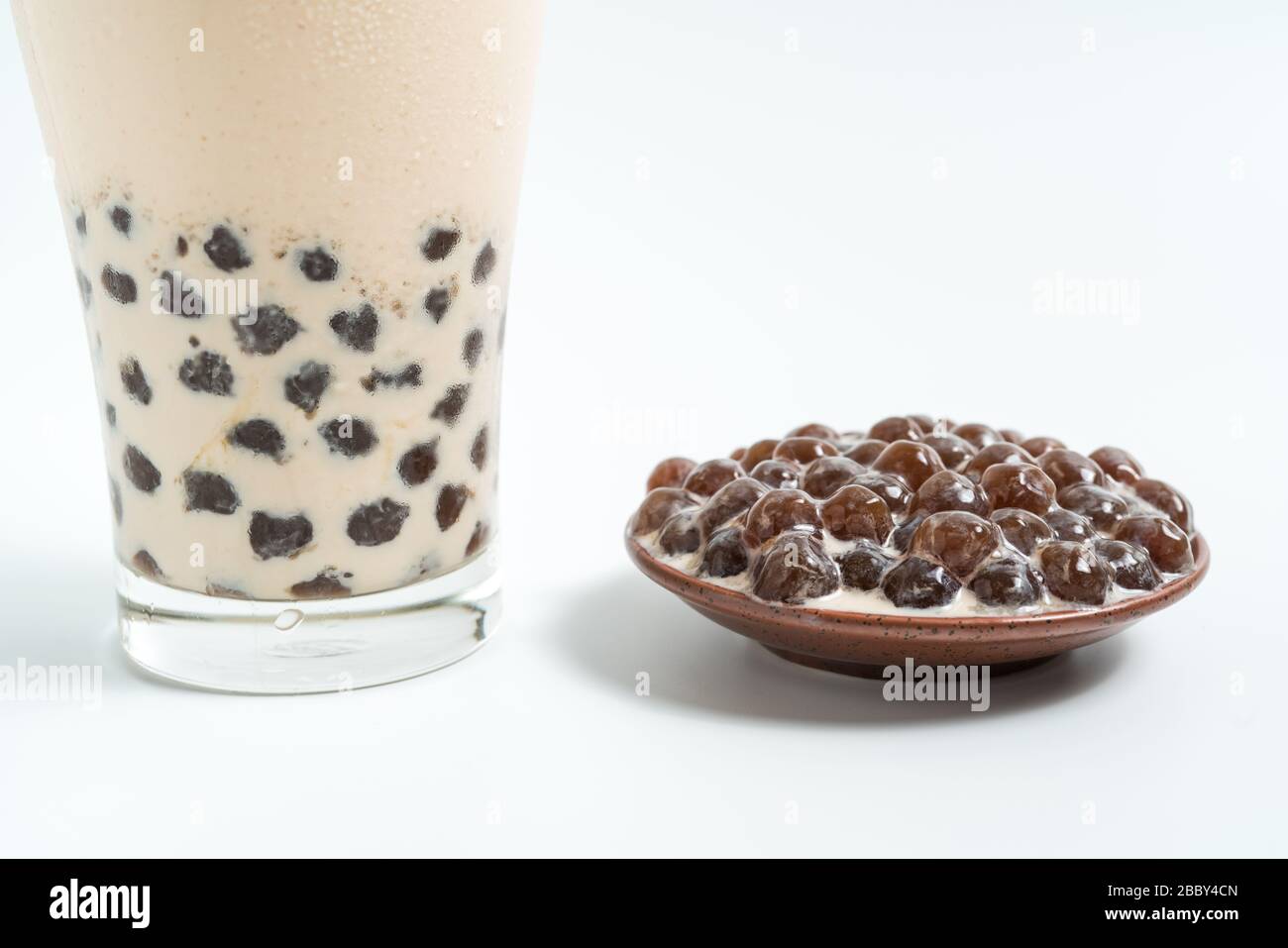 A glass cup of pearl milk tea (also called bubble tea) and a plate of ...