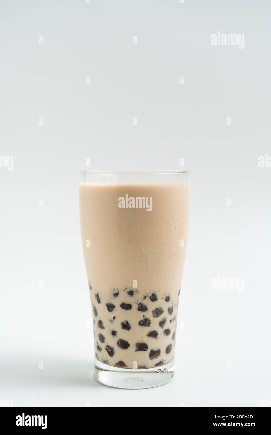 A glass cup of pearl milk tea (also called bubble tea) and a plate of ...
