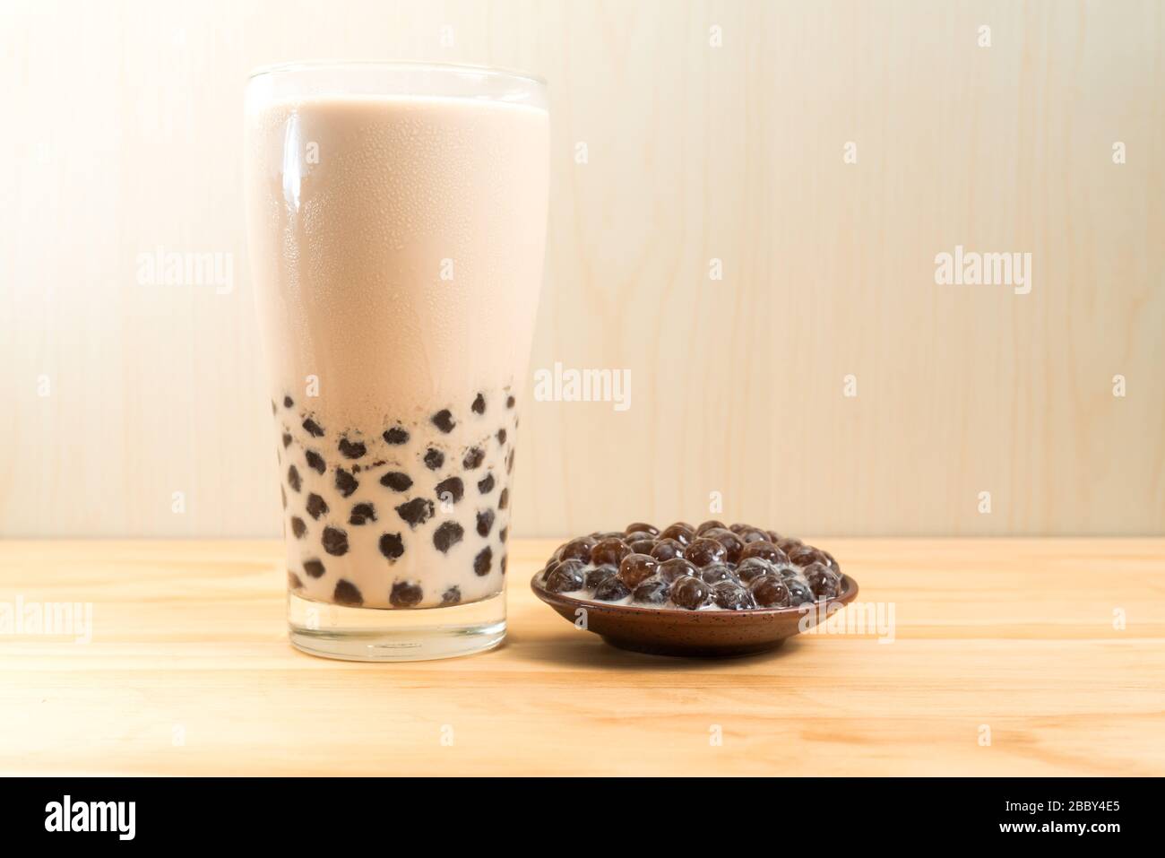 A glass cup of pearl milk tea (also called bubble tea) and a plate of ...