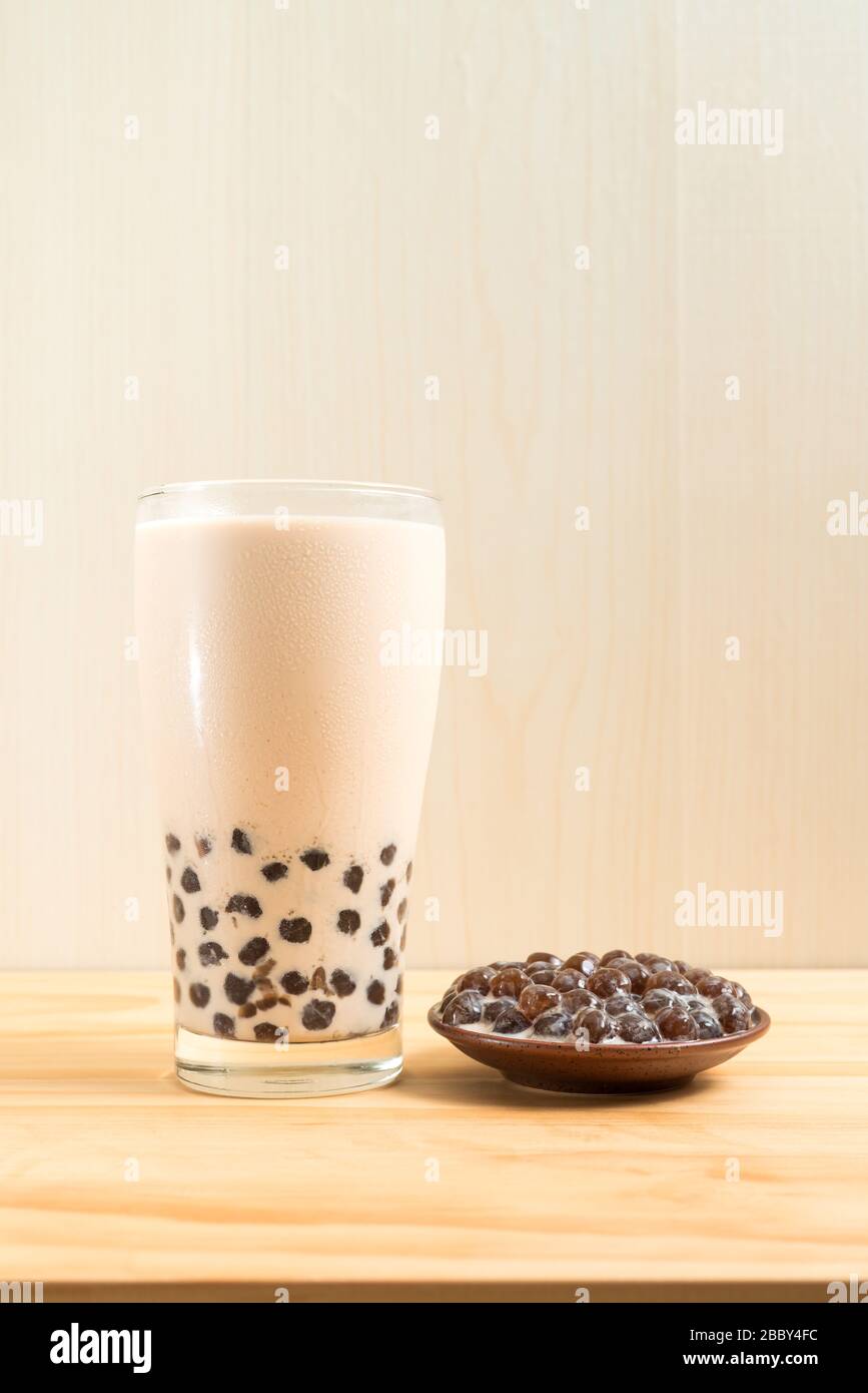 A glass cup of pearl milk tea (also called bubble tea) and a plate of ...