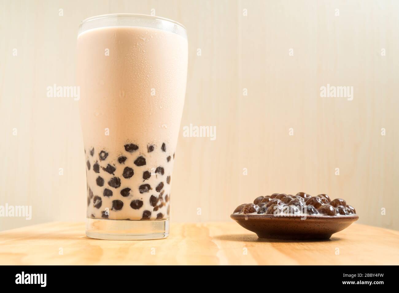 A glass cup of pearl milk tea (also called bubble tea) and a plate of ...